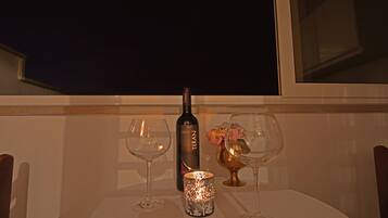 Uma mesa com uma garrafa de vinho, duas taças de vinho e uma vela acesa.