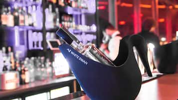 Uma área de bar com bancada azul e um banquinho preto.