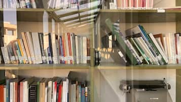 Uma biblioteca com estantes cheias de livros, uma máquina de escrever e uma vitrine de vidro.