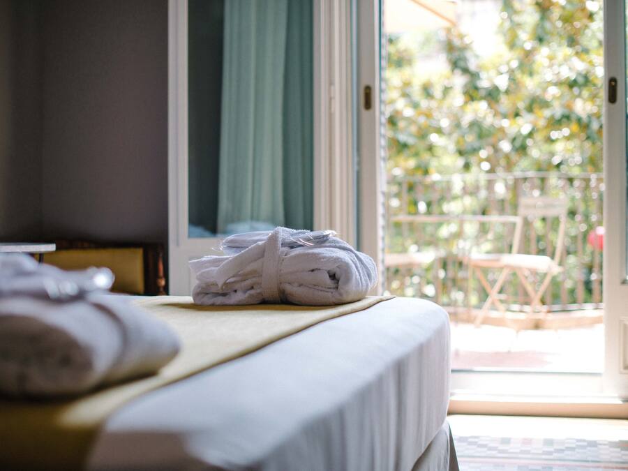 Quarto de hotel com cama, janela e vista para uma varanda.