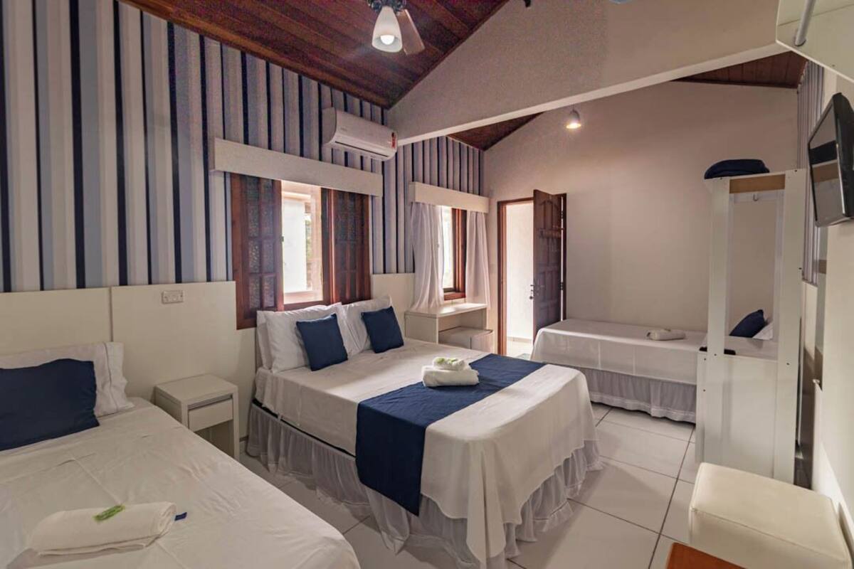 Quarto de hotel com duas camas, um espaço de estar e banheiro.