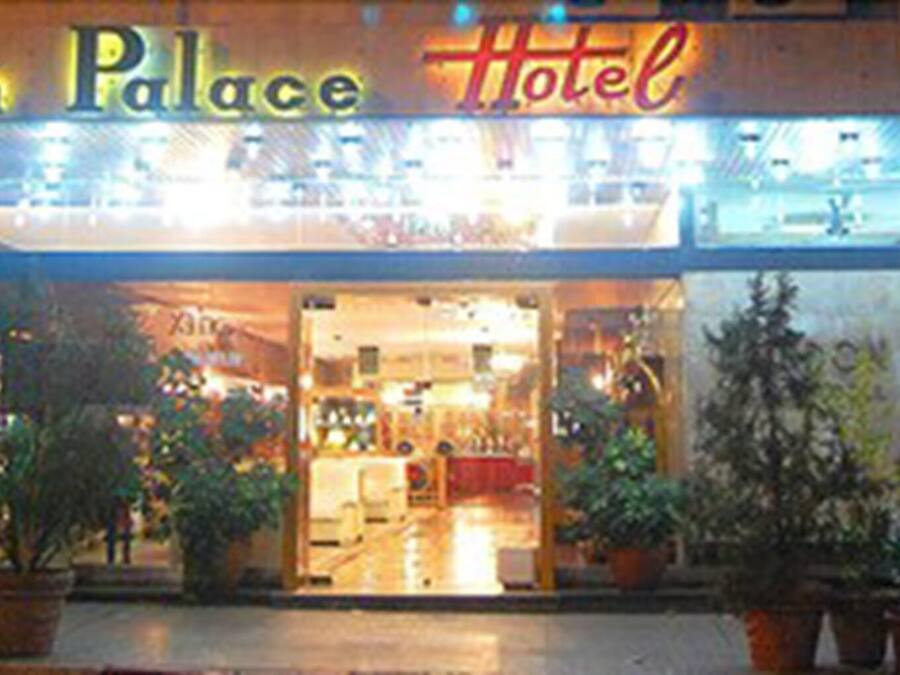 Exterior do Hotel London Palace, com uma entrada bem iluminada e plantas em vasos à frente.