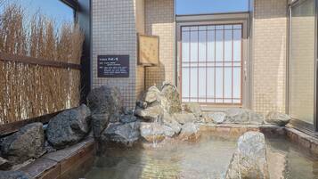 Uma onsen japonesa tradicional com banhos de pedra e uma parede de azulejos.