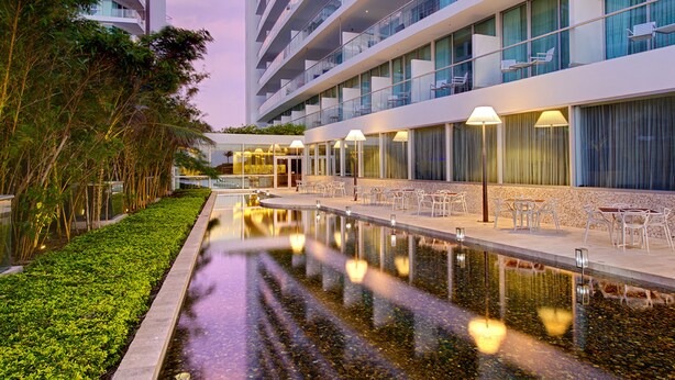 Um hotel moderno com piscina, área de estar ao ar livre e um jardim bem cuidado.