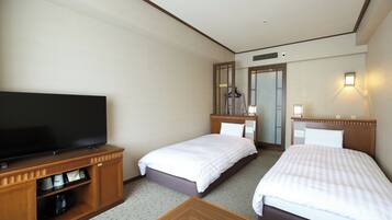 Quarto de hotel com duas camas, televisão, máquina de café e uma pequena mesa.