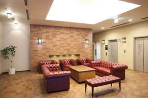 Um hall com parede de tijolos, sofás de couro, mesa de centro de madeira e planta em vaso.