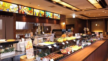 Buffet com diversos alimentos e uma janela de vitrais acima.