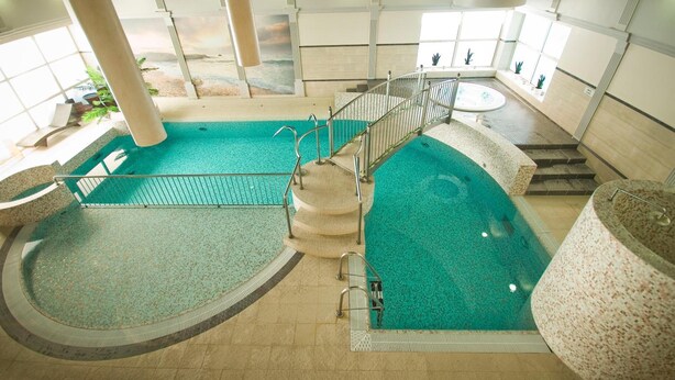 Piscina interior com vários níveis e uma escadaria central.