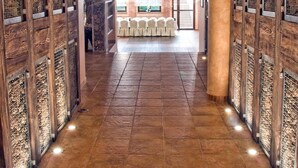 Um corredor com portas de madeira estampadas e chão de azulejos, que leva a uma área de estar com cadeiras.