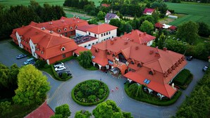 Um hotel grande com vários edifícios de telhado vermelho, um pátio central e campos verdes ao redor.
