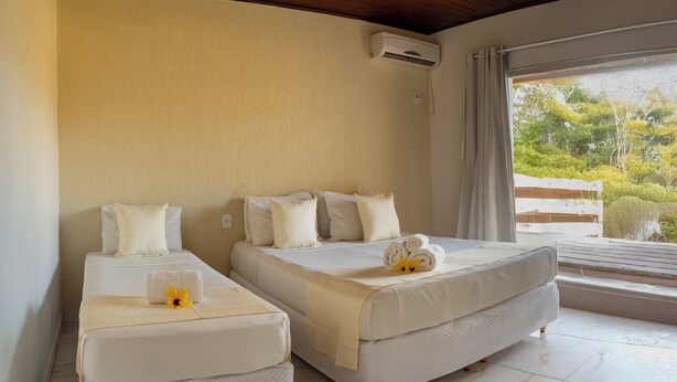 Duas camas de solteiro com roupa de cama branca, piso de mármore e janela com vista para o verde.