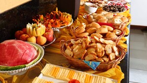 Mesa de buffet com diversos alimentos, incluindo frutas, doces e carnes.