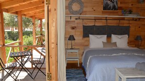 Um quarto de madeira com uma cama, uma mesinha e uma cadeira.