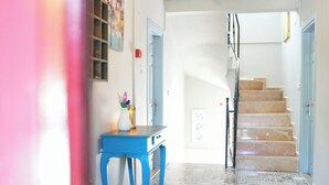 Um corredor com uma mesa azul, escada e pisos com padrão.