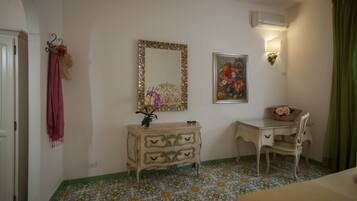 Quarto com cômoda, cadeira, espelho e um quadro na parede.