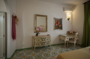 Quarto com cômoda, cadeira, espelho e um quadro na parede.