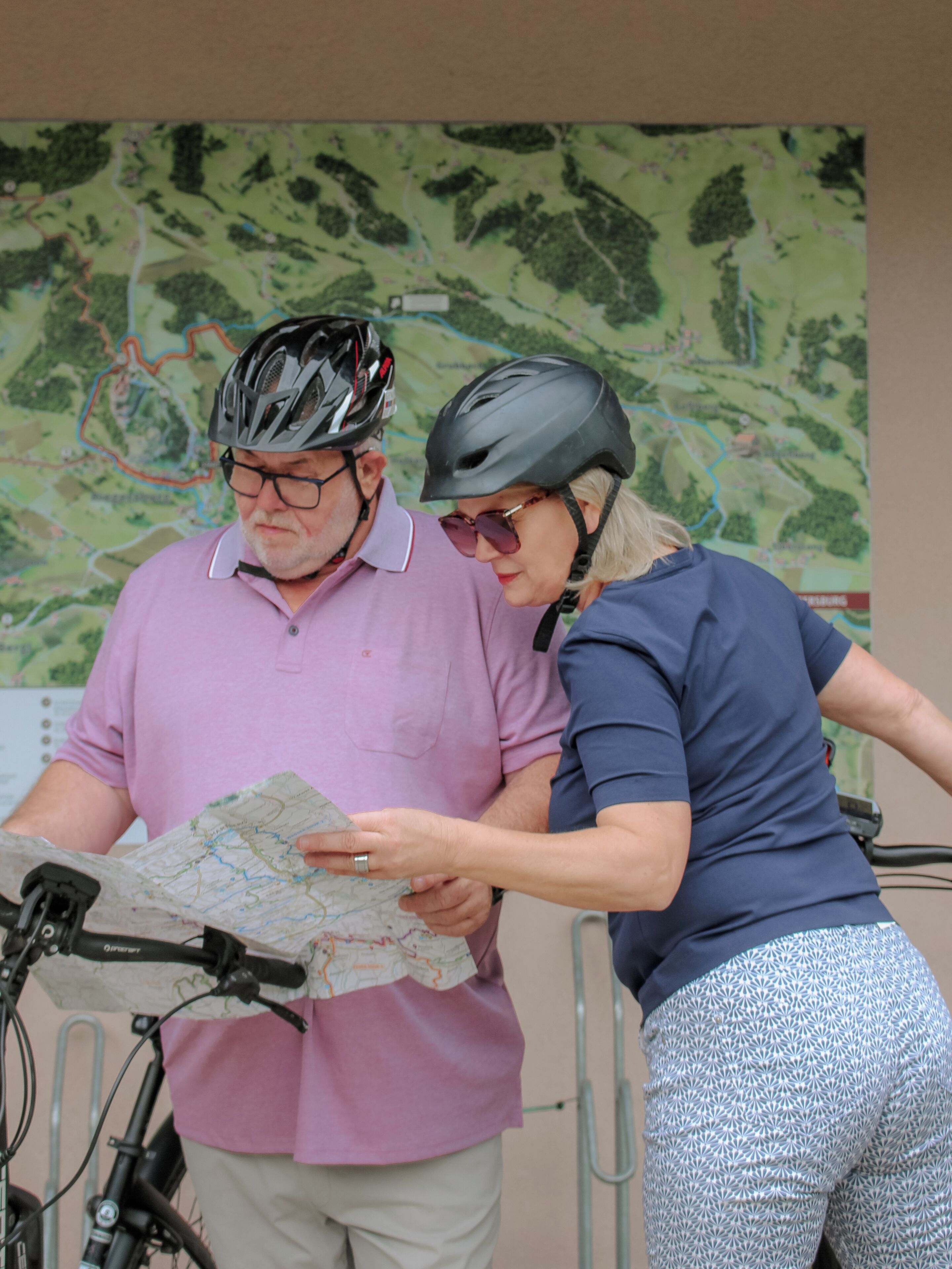Duas pessoas analisando um mapa, uma delas em uma bicicleta.