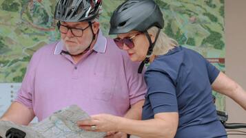 Duas pessoas analisando um mapa, uma delas em uma bicicleta.