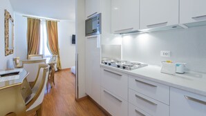 Uma cozinha moderna com armários brancos, fogão e micro-ondas. Há uma área de jantar com mesa e cadeiras.