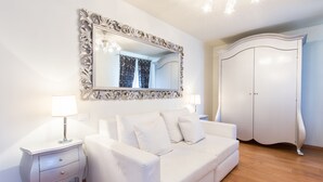 Quarto com sofá branco, um espelho grande, guarda-roupa e duas luminárias de cabeceira.