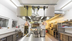 Uma cozinha comercial moderna com eletrodomésticos de aço inoxidável, uma ilha central e iluminação pendente.