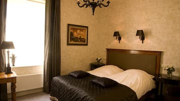Quarto com cama grande, lustre, pintura e janela com cortinas.