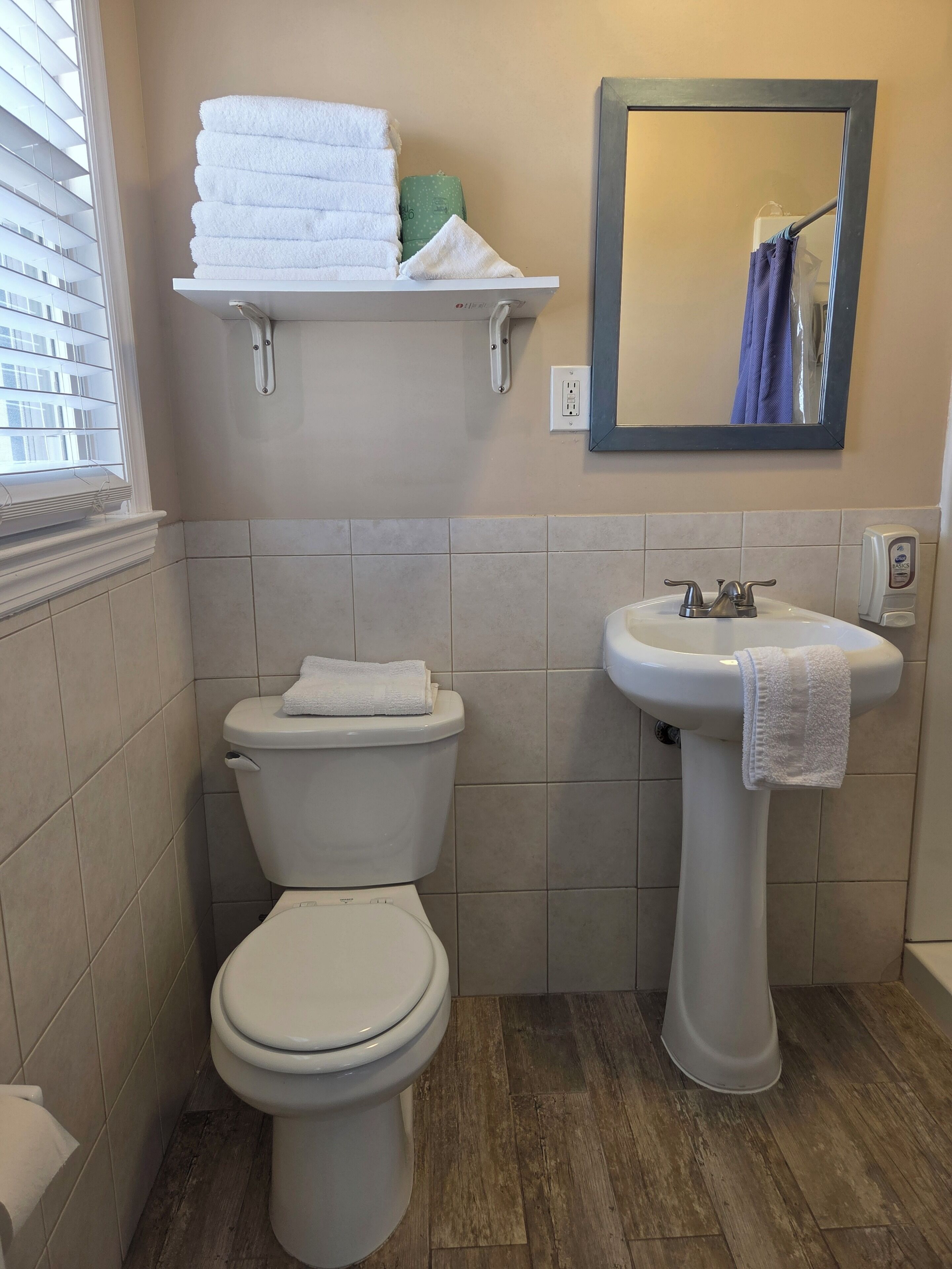 Casa de banho com sanita, lavatório e um porta-toalhas com toalhas dobradas.