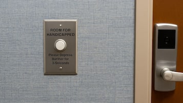 Uma porta com placa indicando aposento para pessoas com deficiência e um botão para acionar a abertura por 3 segundos.