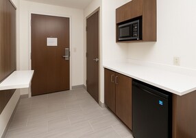 Uma cozinha compacta equipada com micro-ondas, lava-louças e armários de madeira.