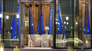 Um hall de hotel moderno com fachada de vidro, cortinas elegantes e uma área de estar bem iluminada.