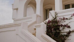 Um edifício branco com janelas em arco e uma escadaria.