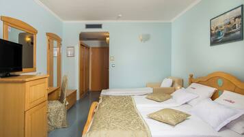 Quarto de hotel com cama, televisão, cómoda de madeira e um quadro na parede.