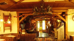 Um espaço de bar acolhedor com mesa de futebol, balcão de madeira e um letreiro indicando "TOILETS".