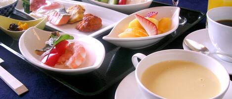 Uma bandeja com diversos pratos, incluindo frutos do mar, frutas e uma tigela de sopa.