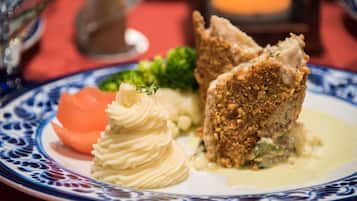 Um prato com comida que inclui um pedaço de frango empanado, uma porção de creme e uma fatia de salmão.