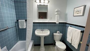 Um banheiro com pia de pedestal, vaso sanitário e banheira.