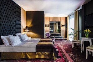 Quarto de hotel com uma cama grande, uma escrivaninha, uma cadeira, uma televisão e vista para o exterior.