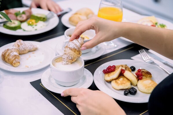 Mesa de café da manhã com pratos de comida, uma xícara de café e um copo de suco de laranja.