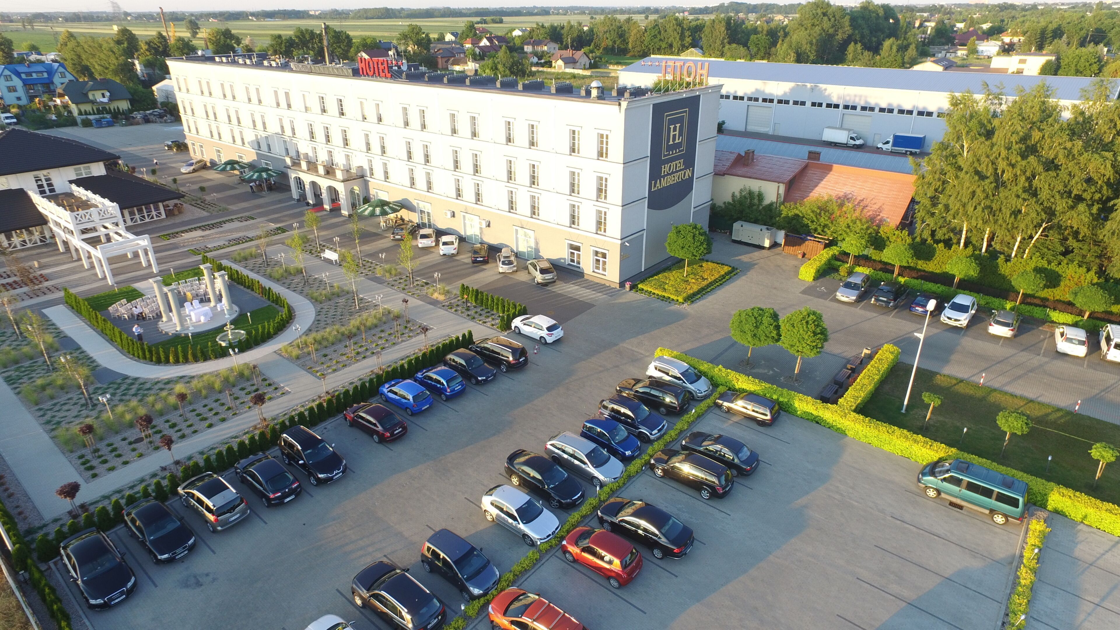 Hotel com estacionamento, fonte e jardim ajardinado.