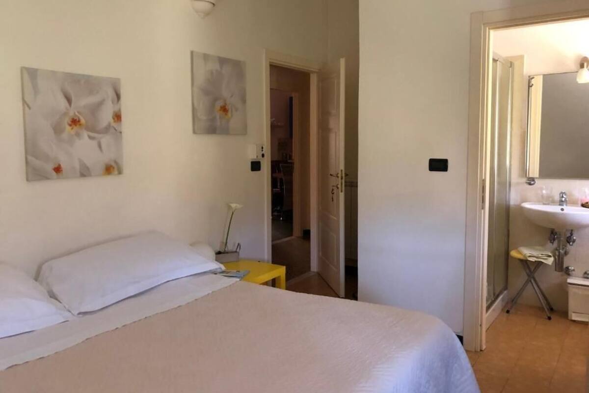 Quarto com cama, mesa de cabeceira, espelho e banheiro com pia.