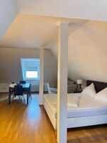 Quarto moderno e bem iluminado com uma cama, uma escrivaninha e uma cadeira.