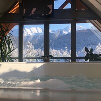 Quarto com grandes janelas com vista para uma paisagem nevada de montanhas.