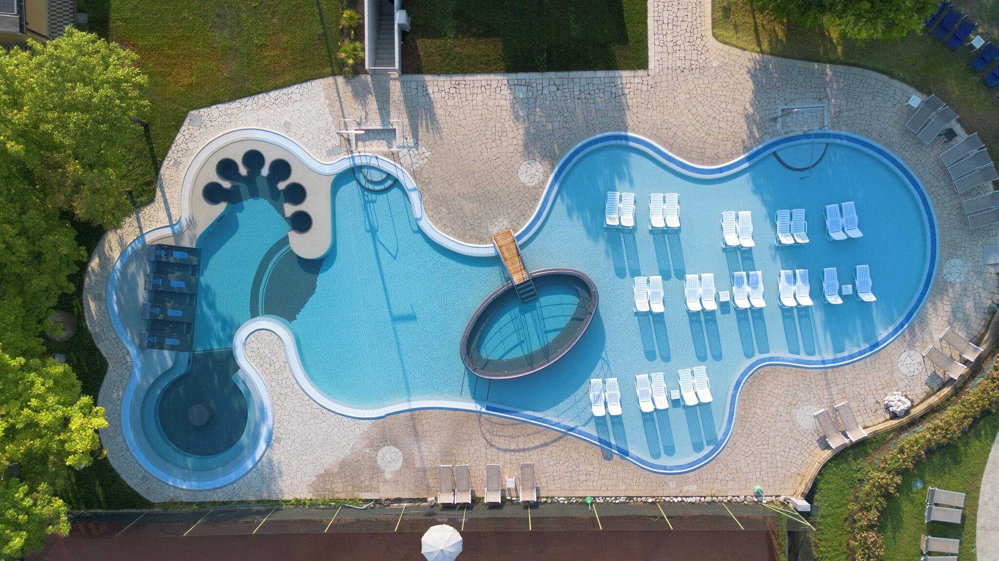 Vista aérea de uma piscina com espreguiçadeiras e uma pequena banheira de hidromassagem.