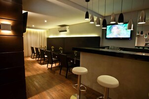 Uma cozinha moderna com área de jantar, banquetas e uma televisão fixada na parede.