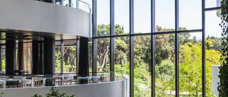 Um interior moderno com grandes janelas, uma escada e um espaço para refeições.