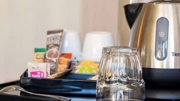Uma cafeteira, um copo e vários sachês de café sobre uma bandeja.