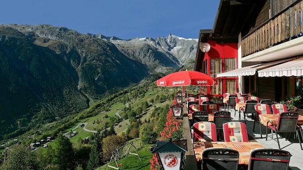 Restaurante com área externa e mesas com vista para uma paisagem montanhosa.