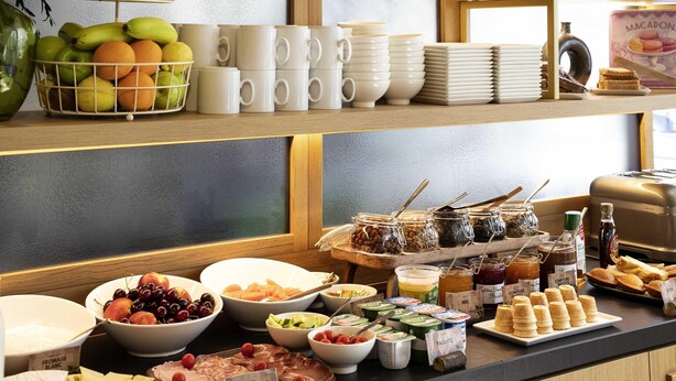 Buffet com diversos alimentos, incluindo frutas, queijos e doces.