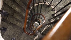 Escada em espiral com corrimão de metal e piso de tela.