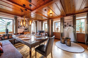Uma sala de jantar espaçosa com uma mesa de madeira posta para quatro pessoas, rodeada por assentos confortáveis.